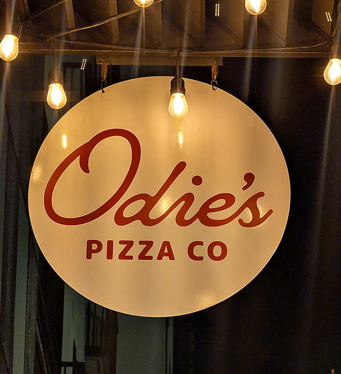 That illuminated sign glows like a pizza lighthouse, guiding hungry souls through the darkness toward sourdough salvation. Follow the light!