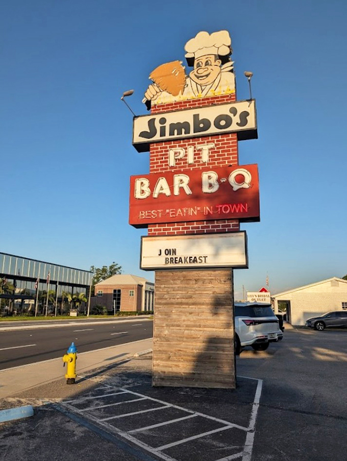 The cheerful chef mascot on the sign extends a permanent invitation to discover what real pit barbecue tastes like.