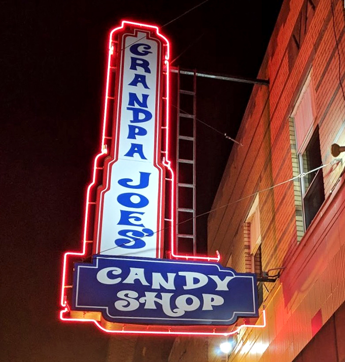 The neon sign illuminates the darkness, serving as both advertisement and nightlight for grown-ups with candy dreams.