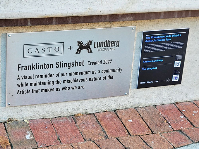 The plaque reveals The Franklinton Slingshot's creation story &ndash; a visual reminder of community momentum with a mischievous artistic spirit.