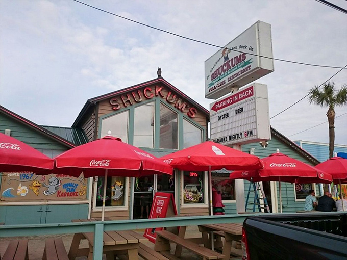 The Shuckums sign stands proud against the Florida sky like a lighthouse for hungry travelers. Those red umbrellas aren't just shade&mdash;they're beacons of deliciousness.