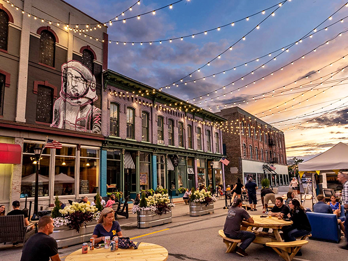 Downtown Bay City comes alive at dusk, where string lights create a magical canopy over historic streets bustling with outdoor diners.
