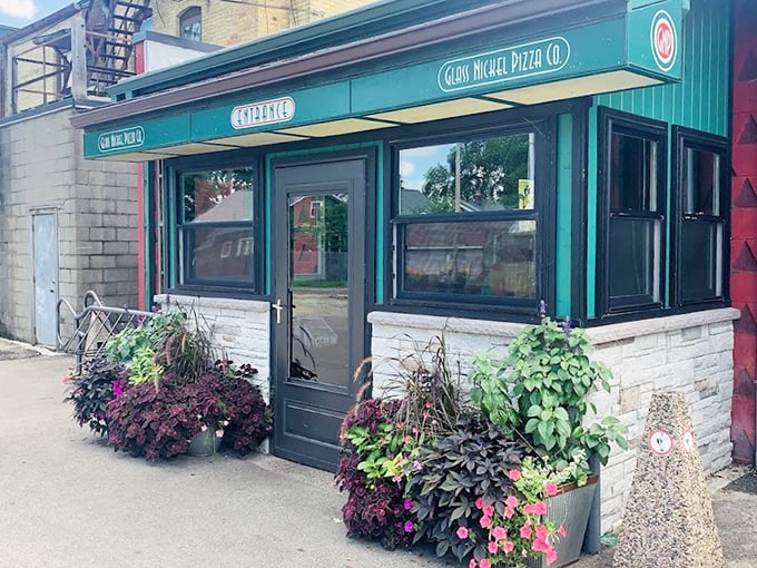 The charming green storefront of Glass Nickel Pizza Co. welcomes you with colorful flower pots &ndash; like your favorite neighbor who always has something delicious in the oven.