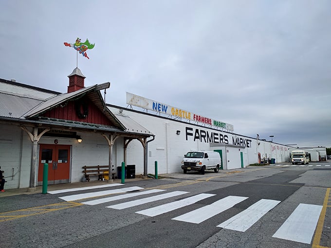 The iconic red barn entrance of New Castle Farmers Market stands like a gateway to bargain paradise.