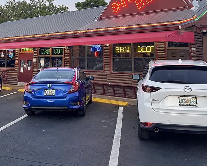 Shiver's BBQ's neon signs glow like beacons of hope for hungry travelers. The log cabin exterior promises authentic, no-nonsense barbecue inside.