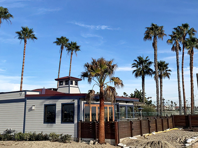 Palm trees frame this coastal gem like nature's own welcome sign. Blue-gray siding and large windows promise ocean views with every bite.