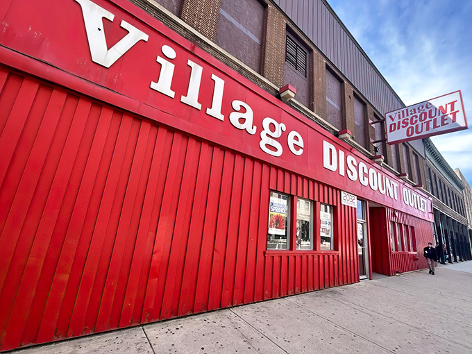 The bright red Village Discount Outlet sign beckons like a lighthouse for bargain hunters. This Chicago treasure trove awaits with endless aisles of possibility.