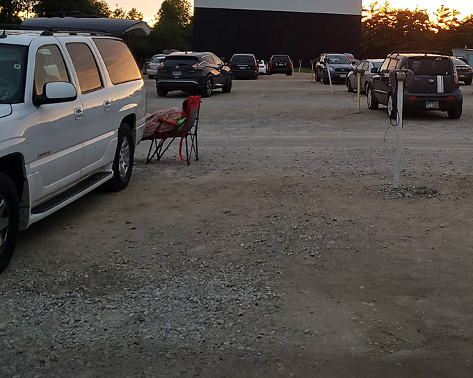 Families settle in with lawn chairs and blankets, creating their perfect movie-watching spots under the darkening sky.
