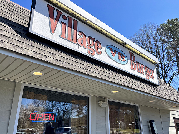 The iconic Village Burger sign beckons hungry travelers like a lighthouse for the famished. Simple, straightforward burger bliss awaits inside.