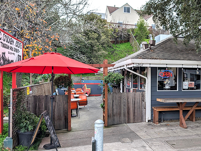 A splash of color welcomes hungry visitors to this cozy patio, where bright orange umbrellas promise both shade and culinary delights.