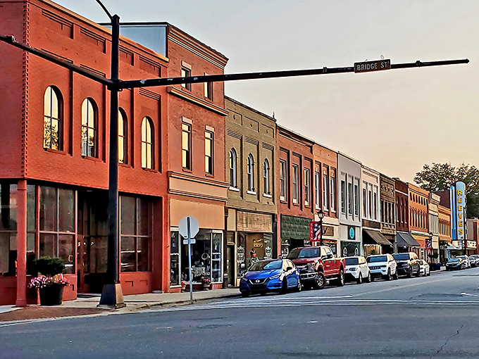Bridge Street's colorful storefronts catch the golden hour light, transforming ordinary brick into a warm palette that would make any Instagram filter jealous.