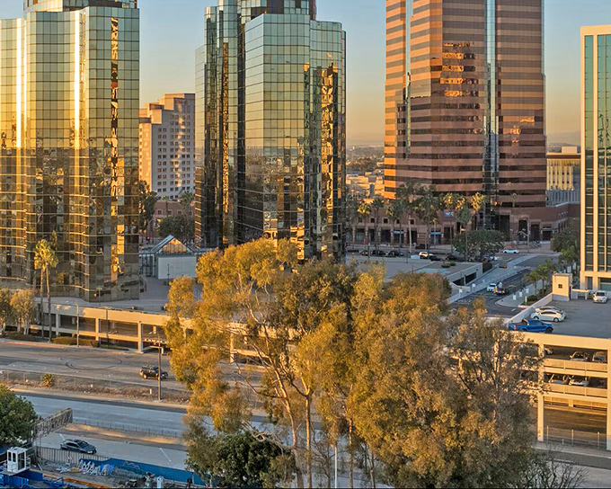 Downtown Long Beach's glass towers catch the sunset like giant copper pennies, a glittering backdrop for treasure hunters exploring the streets below.