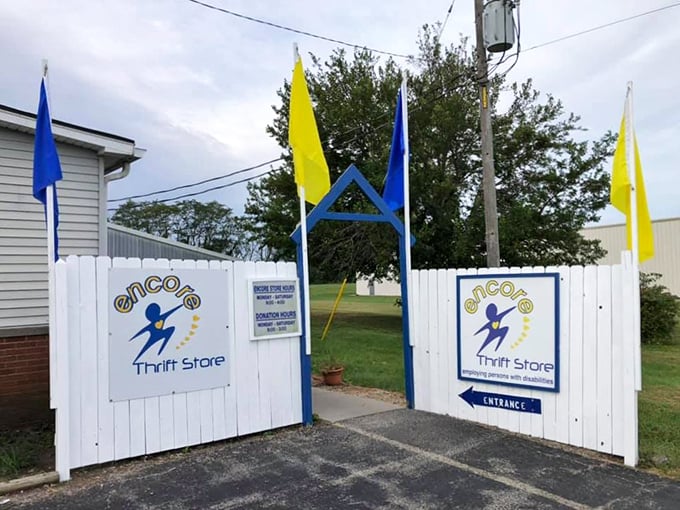 Welcome to thrift nirvana! The cheerful white picket fence entrance with its blue and yellow flags signals you're about to enter a world where $25 fills an entire cart.
