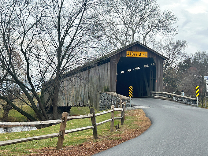 The approach to history&mdash;weathered wood, stone foundations, and that iconic yellow clearance sign warning modern vehicles what horse-drawn wagons never worried about.