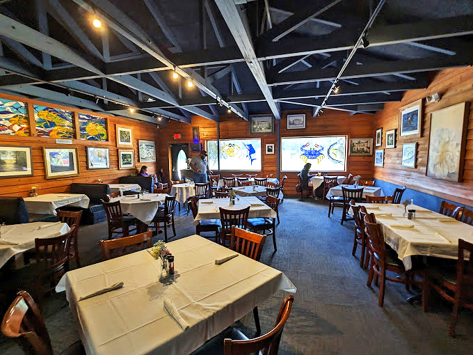 Inside, the warm wooden interior feels like a maritime gallery, with local artwork adorning the walls and white tablecloths promising something beyond your average seafood shack.