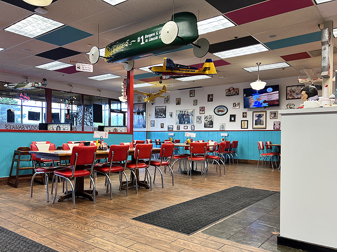 Classic red vinyl booths, checkerboard ceiling, and model airplanes suspended in flight—this isn't decoration, it's a time machine disguised as a diner.