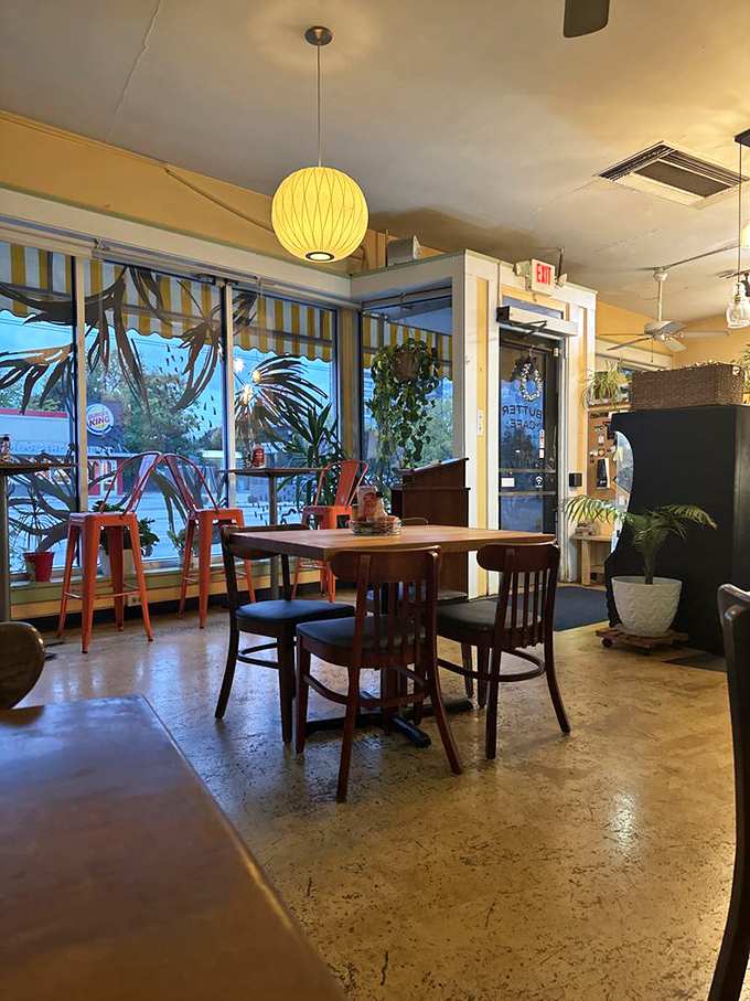 Sunlight streams through windows adorned with tropical art, while hanging plants and eclectic seating create that perfect "stay awhile" atmosphere every neighborhood cafe dreams of.