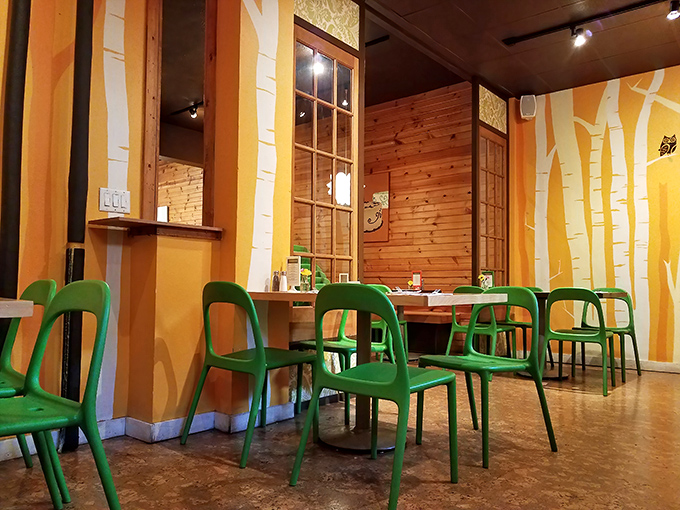 Warm wooden walls adorned with stylized birch trees create a forest-like sanctuary, complete with those signature green chairs.