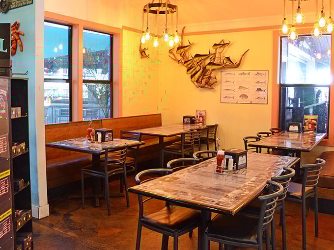 Nautical charm meets dining comfort. Metal fish sculptures swim across the wall while pendant lights cast a warm glow that makes everyone look vacation-tanned.