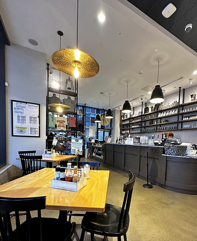 Golden disc lighting fixtures hover above wooden tables like breakfast UFOs, illuminating a space where coffee flows as freely as conversation.