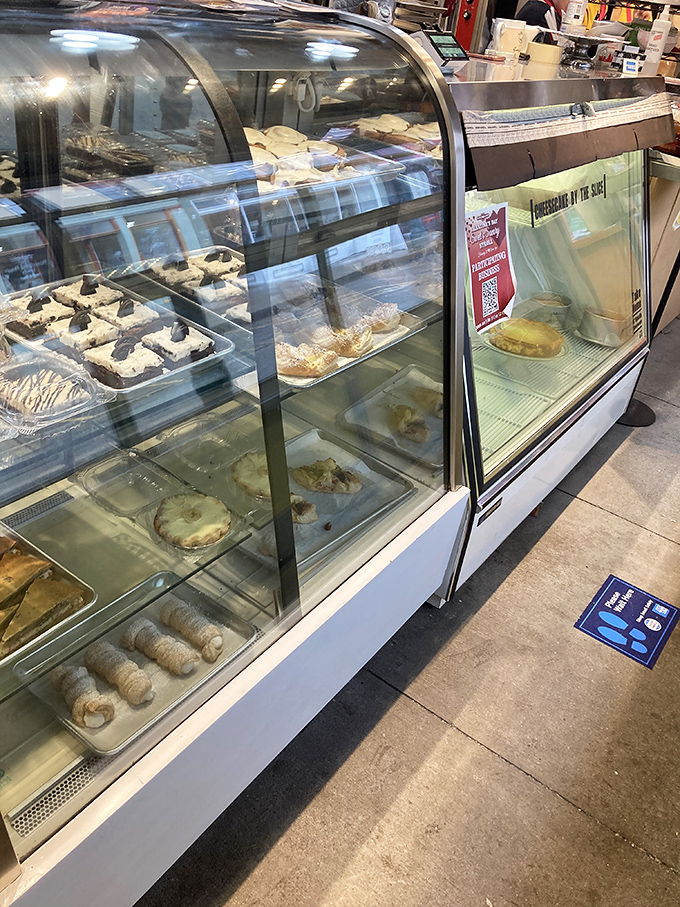 The working kitchen beckons through glass walls, where flour-dusted magic happens daily in full view of eager customers.