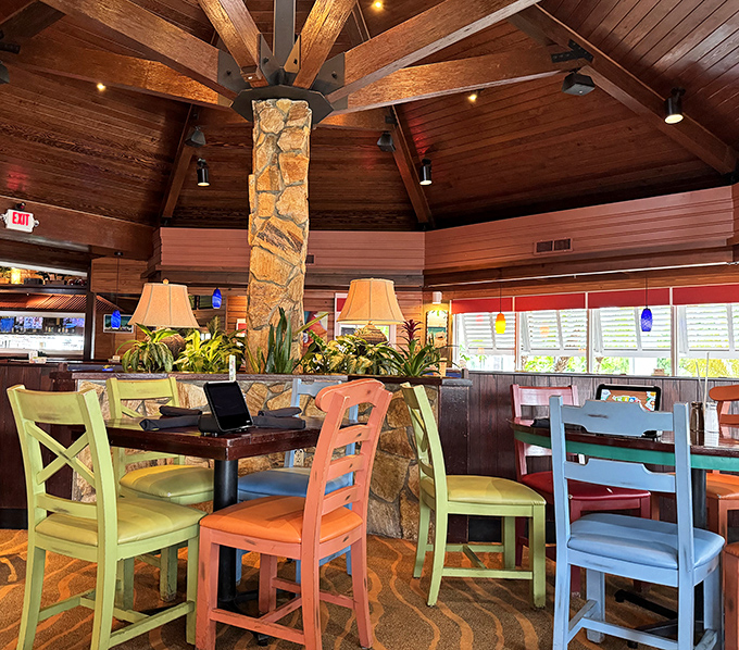 Colorful chairs in lime, coral, and sky blue gather around stone columns beneath soaring wooden ceilings&mdash;architecture that whispers "slow down" before you've even ordered.