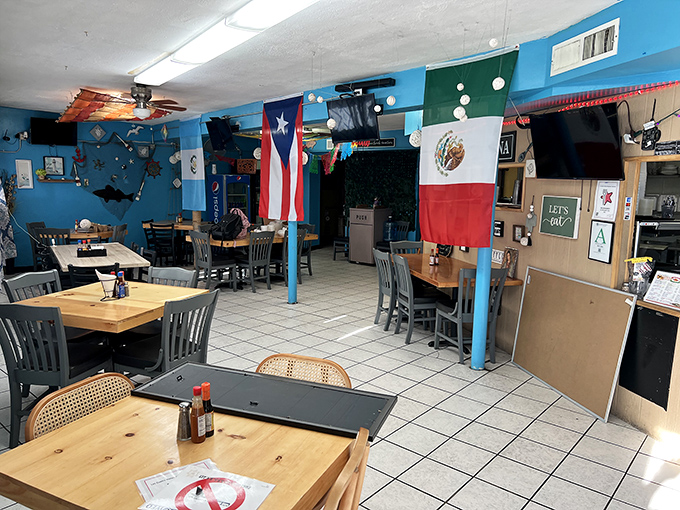 Inside, flags hang proudly from the ceiling while wooden tables invite you to settle in for a feast that transcends the humble surroundings.