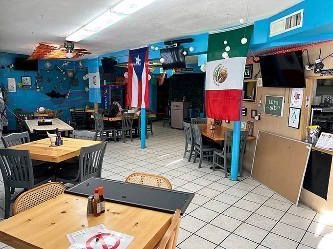 Inside, flags hang proudly from the ceiling while wooden tables invite you to settle in for a feast that transcends the humble surroundings.