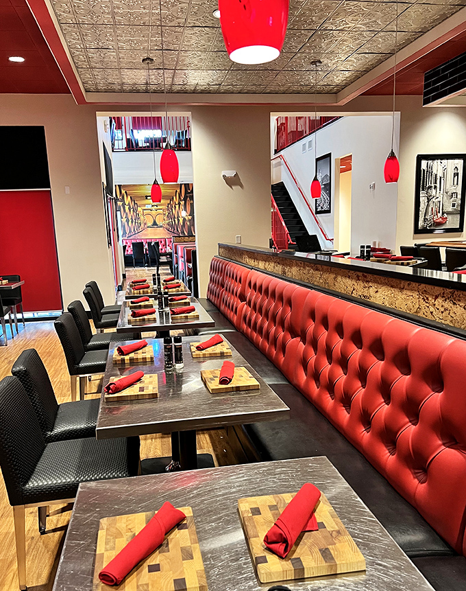 Bold red leather banquettes and sleek modern tables create a dining atmosphere that's both sophisticated and inviting—like a steakhouse that dressed up but isn't taking itself too seriously.