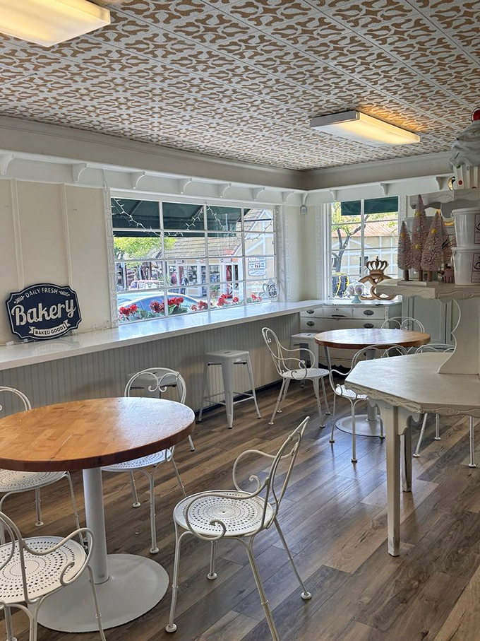 Sunlight streams through windows onto elegant metal chairs and wooden tables, creating a bright sanctuary where pastry dreams come true.