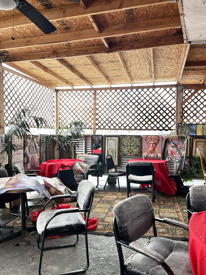 A cozy covered patio with lattice walls, red tablecloths, and eclectic artwork creates an intimate dining space that feels more like a friend's backyard than a restaurant.