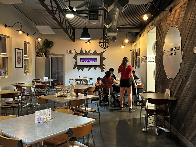 Inside, industrial chic meets coastal comfort with exposed ductwork, pendant lighting, and wooden accents creating an atmosphere where flip-flops and business casual feel equally at home.