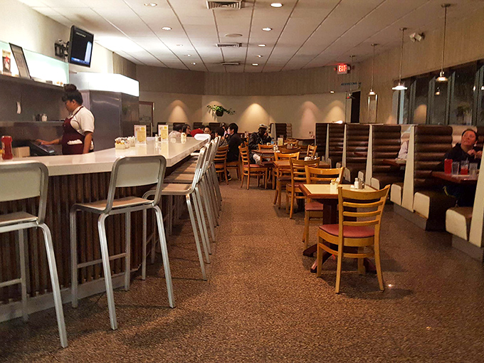 Classic diner aesthetics meet timeless comfort at the counter, where solo diners perch on swivel stools watching the beautiful choreography of short-order cooking.