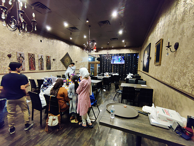 Elegant chandeliers and textured walls transform this space into a dining sanctuary. The contrast between strip mall exterior and refined interior is part of the charm.