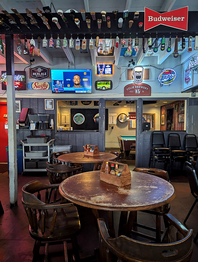 Beer tap handles dangle from the ceiling like trophies of conquests past, while neon signs cast their warm glow across well-worn wooden tables.