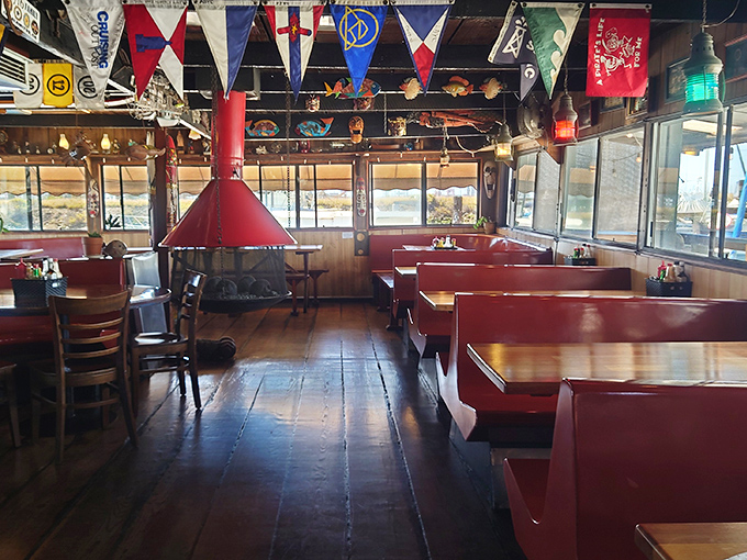 Nautical flags dance overhead while red vinyl booths invite you to settle in. This isn't themed decor&mdash;it's authentic floating restaurant charm.