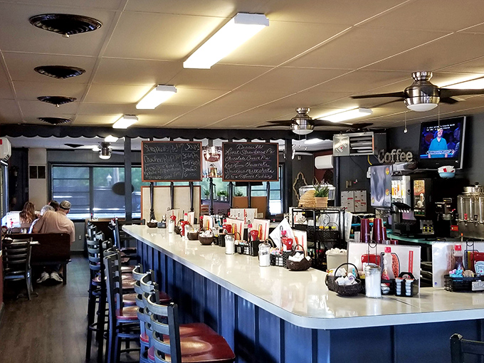 Classic diner counter seating where regulars become family. The blue counter stretches like a runway for breakfast masterpieces, with chalkboards announcing the day's specials.