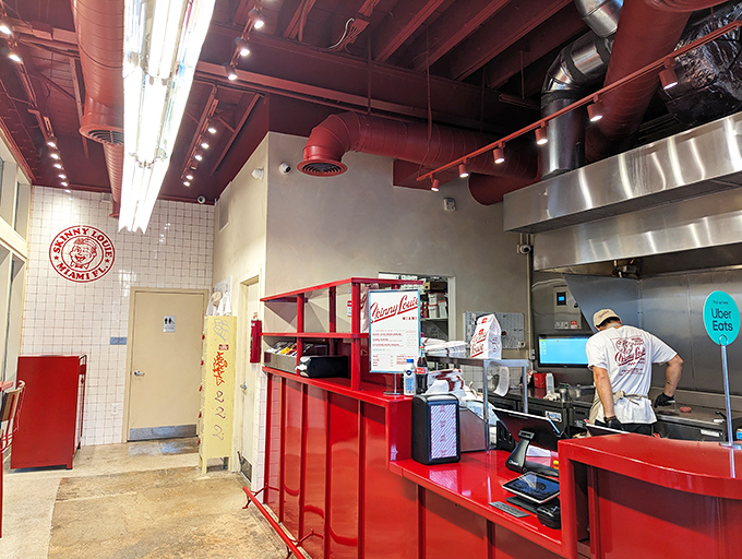 Behind that gleaming red counter, burger magic happens. The exposed ceiling beams and open kitchen create industrial-chic vibes that somehow feel like home.