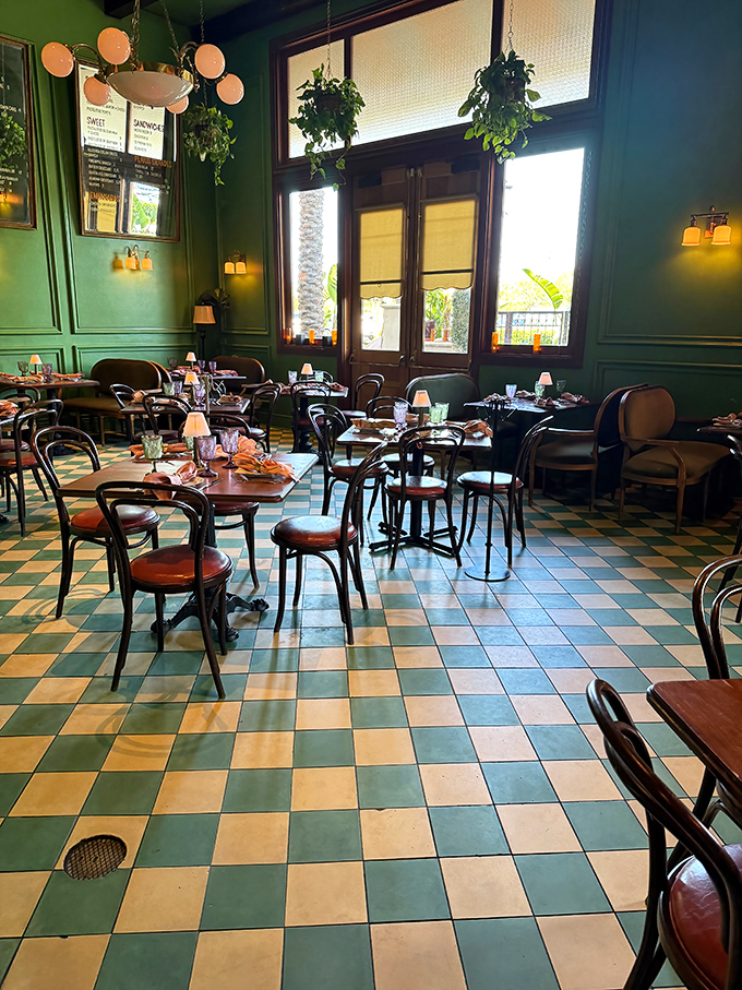 The emerald walls and checkerboard floors aren't just design choices&mdash;they're time machines. Bentwood chairs await your stories while hanging plants create pockets of jungle indoors.