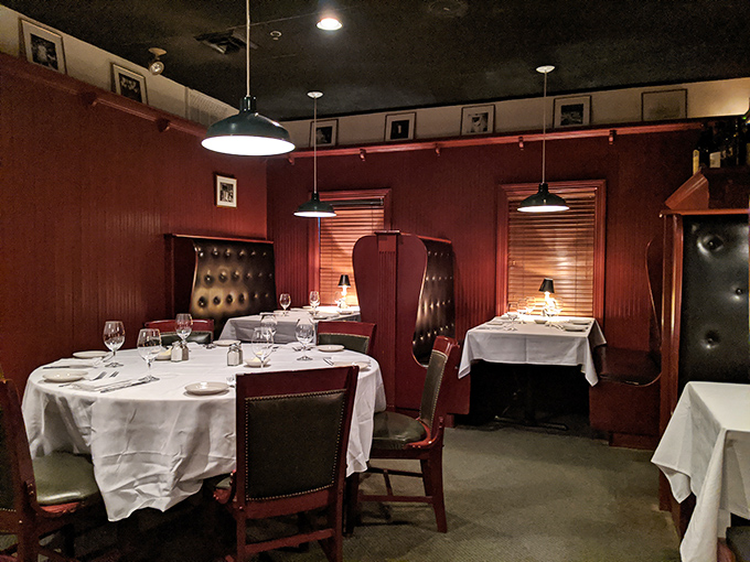 Step into a world where crimson walls, white tablecloths, and leather booths create the perfect backdrop for serious steak business.