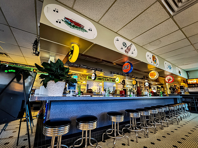 Chrome stools line up at attention along the counter, where vintage gas station signs hang overhead like guardians of a bygone era.