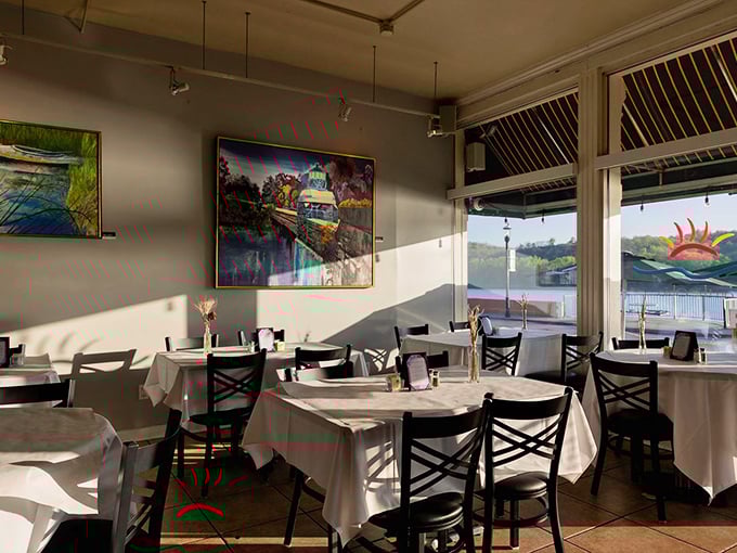 Sunlight streams through windows framing local artwork and river views. This dining room proves ambiance doesn't need to be complicated to be perfect. 