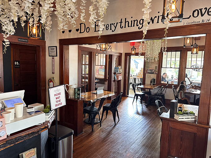 Step inside to discover wooden floors that whisper tales of satisfied diners past, while hanging white florals create an ethereal canopy beneath the "Do Everything with Love" mantra.