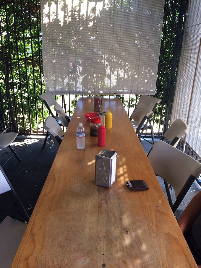 Dappled sunlight filters through bamboo shades at this no-frills outdoor table, where burger magic happens with zero pretension.