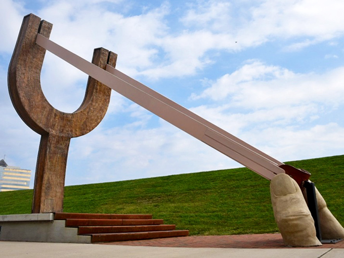 Against a perfect blue Ohio sky, The Slingshot's elegant wooden curves and stretched band create a striking silhouette that transforms physics into public art.