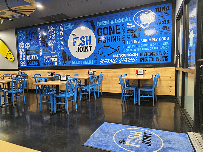 Ocean-blue walls adorned with playful seafood slogans create the perfect backdrop for wooden tables and chairs that say "stay awhile, the fish is worth it."