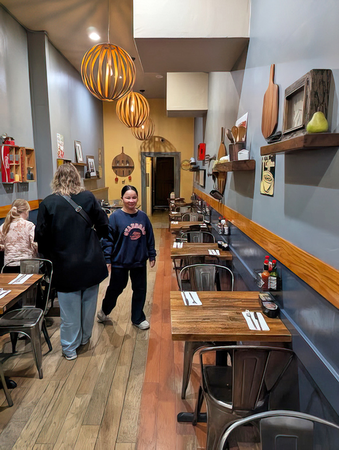 Narrow but mighty, the interior stretches like a railroad apartment where every inch is dedicated to the art of perfect breakfast. Those pendant lights cast a warm glow over morning conversations. 