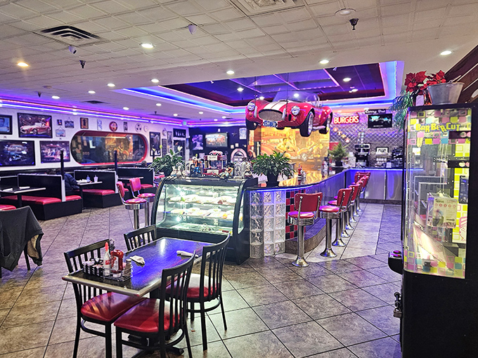 Step inside and the purple-blue neon glow transforms ordinary meals into memorable occasions. That suspended classic car proves gravity is no match for nostalgia.