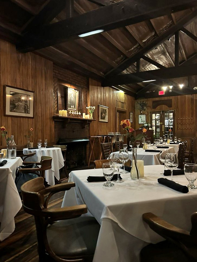 Wood-paneled walls and exposed beams create a dining room that whispers "old-school sophistication" while the fireplace promises warmth beyond just the service.