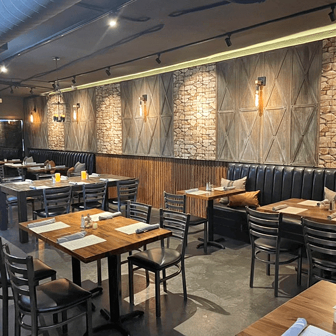 Modern meets rustic in this thoughtfully designed dining room where stone accent walls and comfortable booths set the stage for smoky delights.